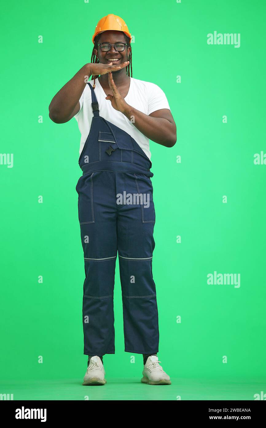 A man in a construction suit on a green background shows a full-length ...