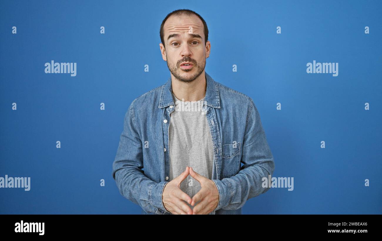 Hispanic bald man with a beard, wearing a denim jacket, poses against ...