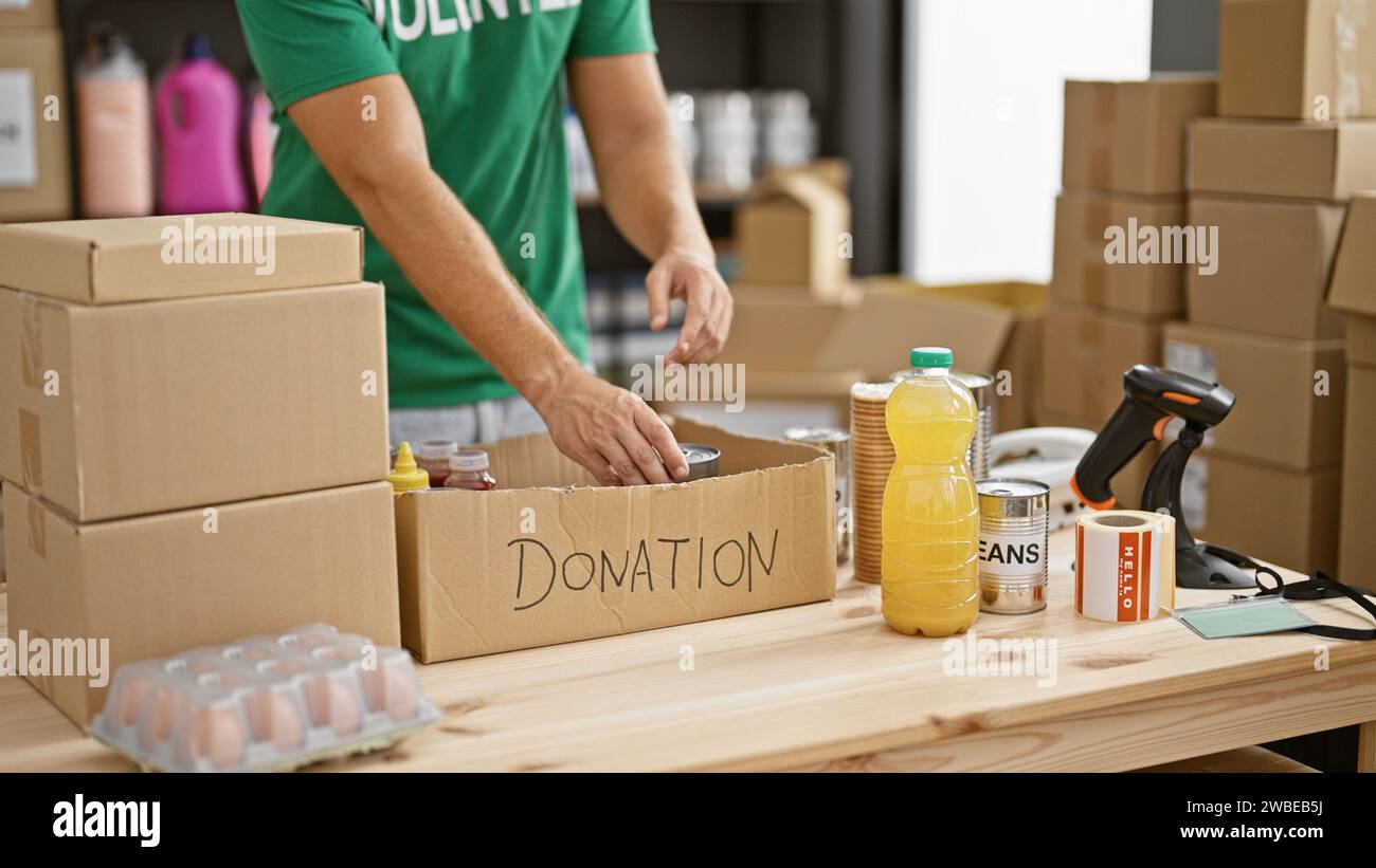 A young man prepares a donation box with food items in a warehouse ...