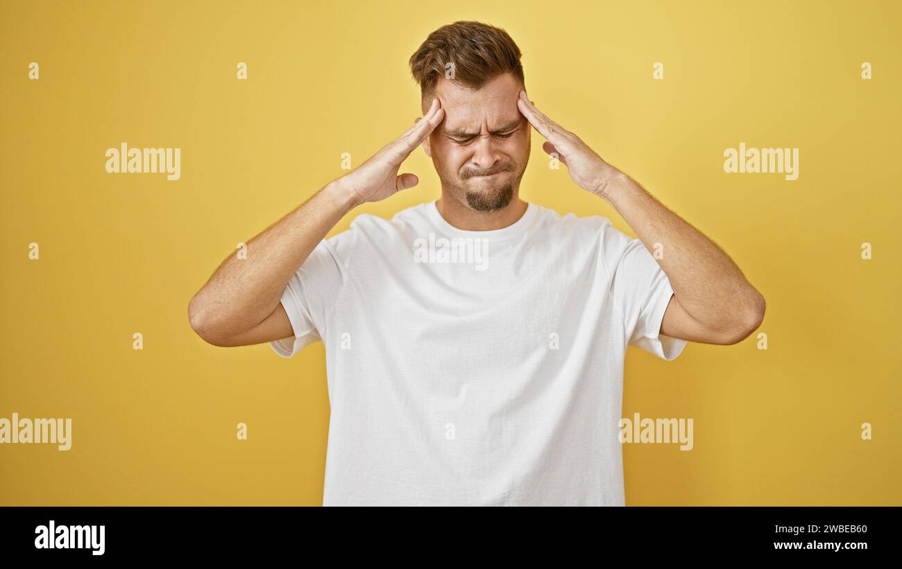 A stressed hispanic man in a white shirt with a beard stands against a ...