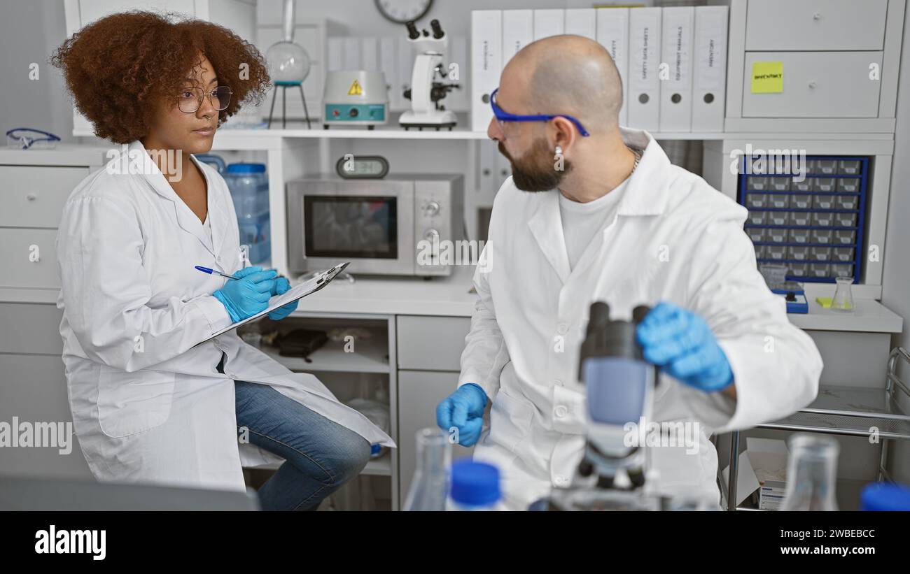 Inside the buzzing lab, two committed scientists, man and woman ...