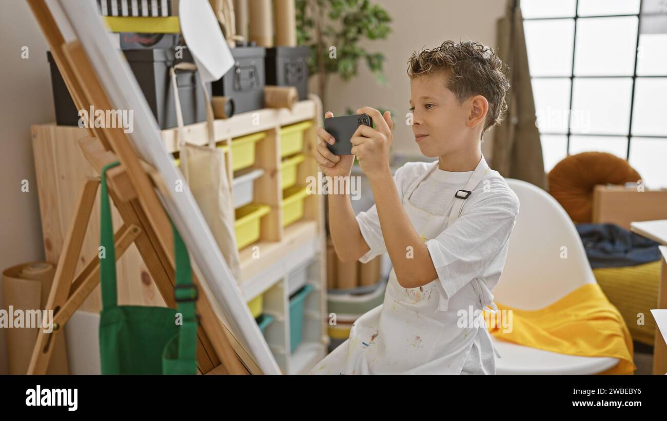 Adorable blond boy artist, smiling as he's taking a picture in an art ...