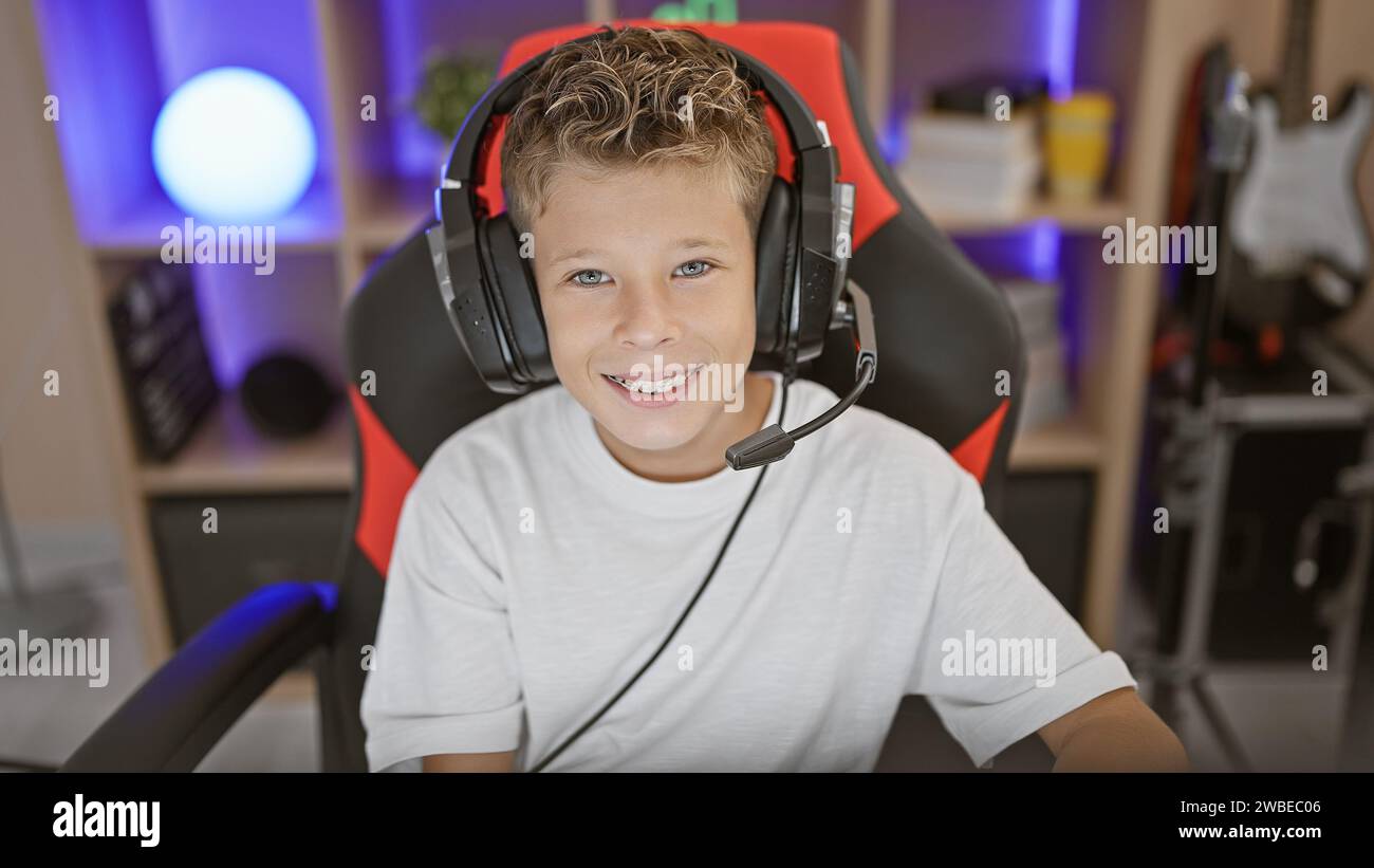 Adorable blond boy streamer happily playing gaming, streaming a video ...