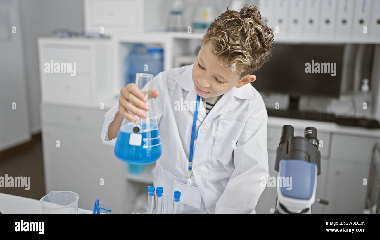 Adorable blond boy scientist, engrossed in crucial medical research ...