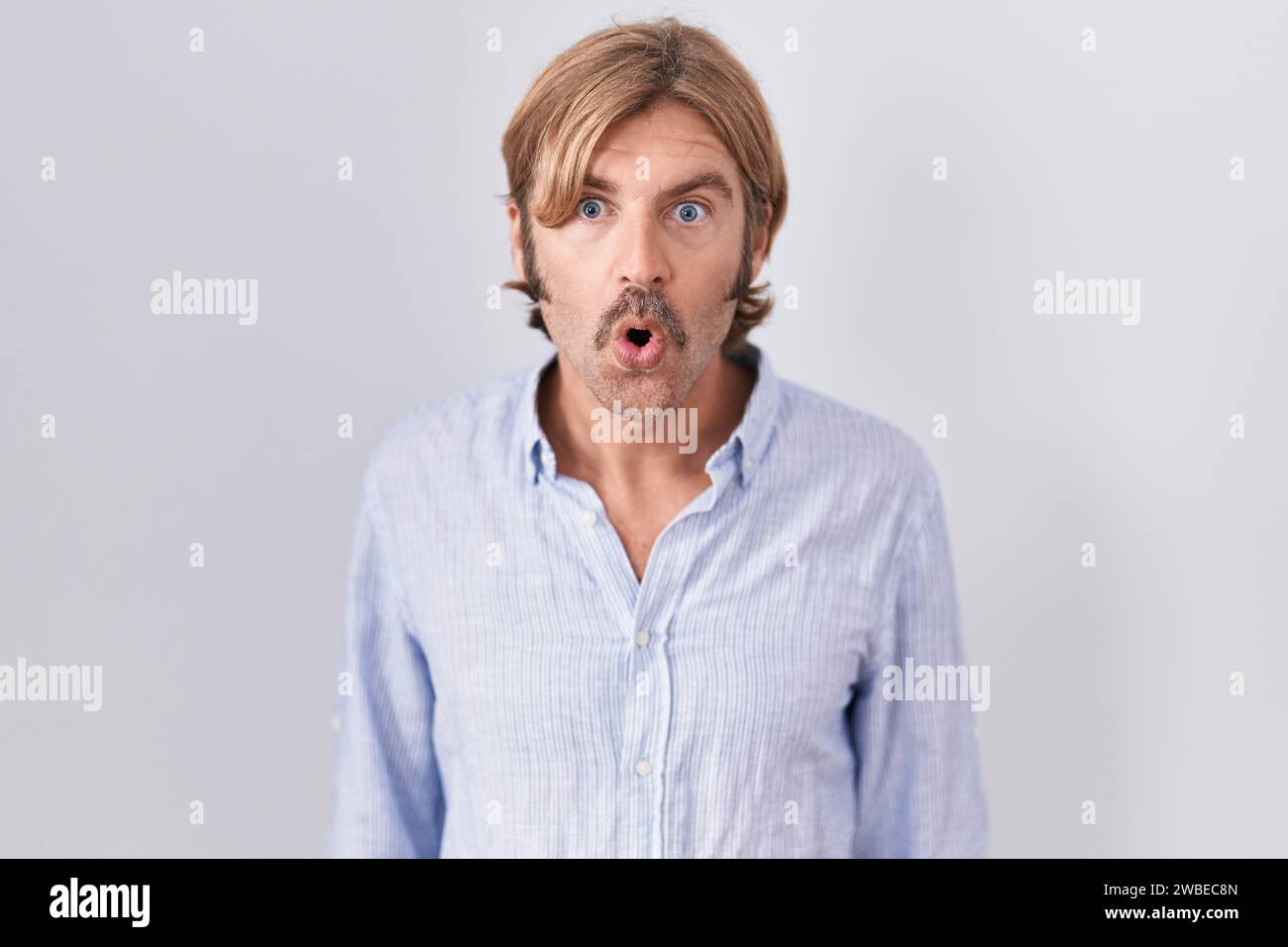 Caucasian man with mustache standing over white background afraid and ...
