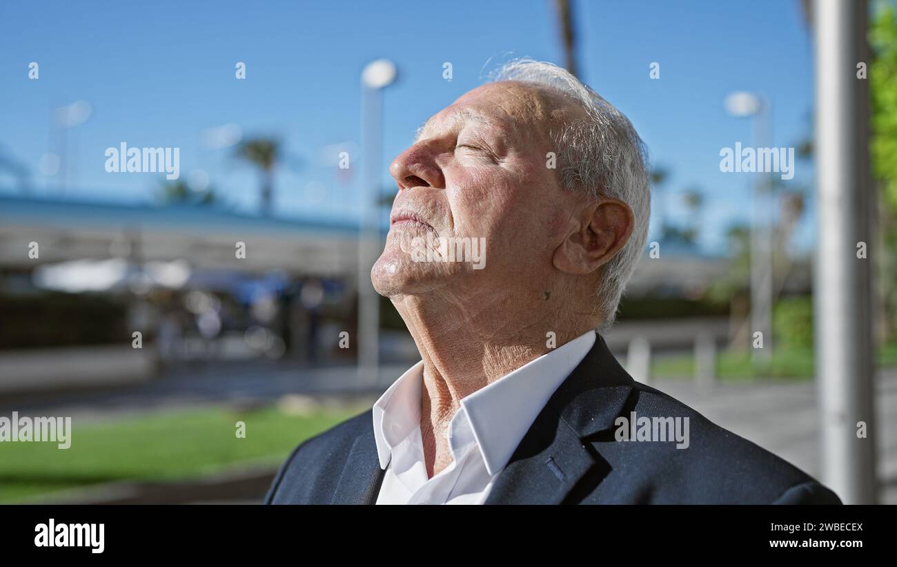 Balanced senior man enjoying meditating, calmly breathing in the city ...