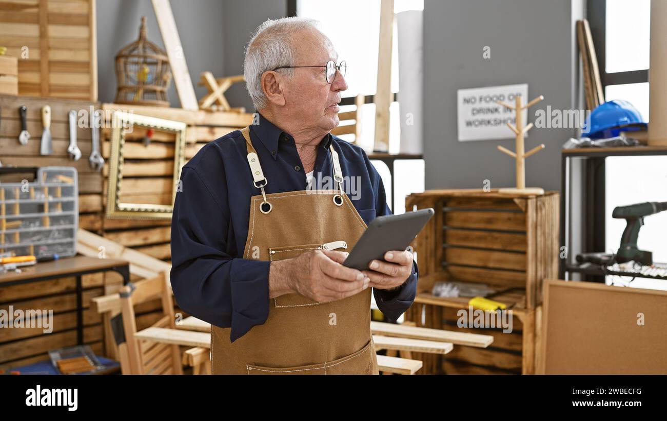Senior man, a serious carpenter with grey hair, looking around his ...