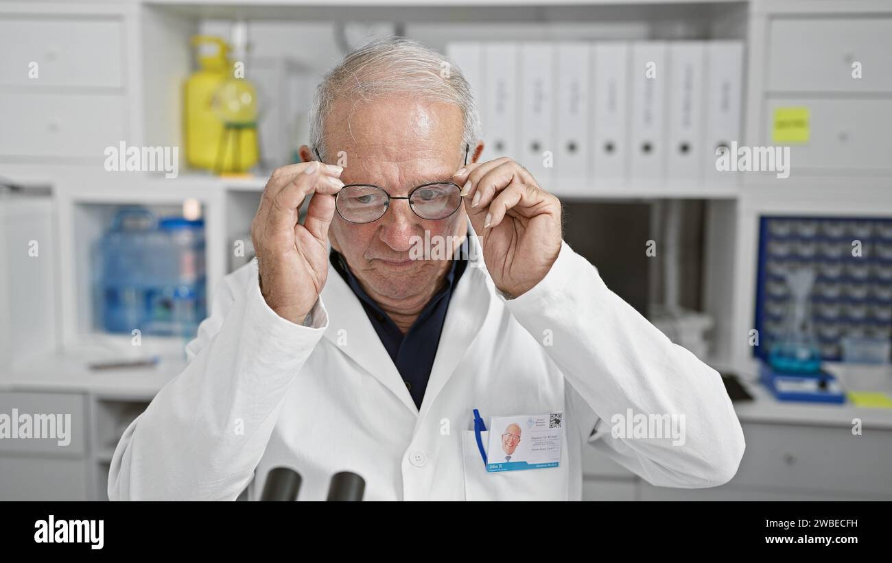 Serious-faced senior man scientist,expressing dedication towards medicine, wood deep in analysis ...