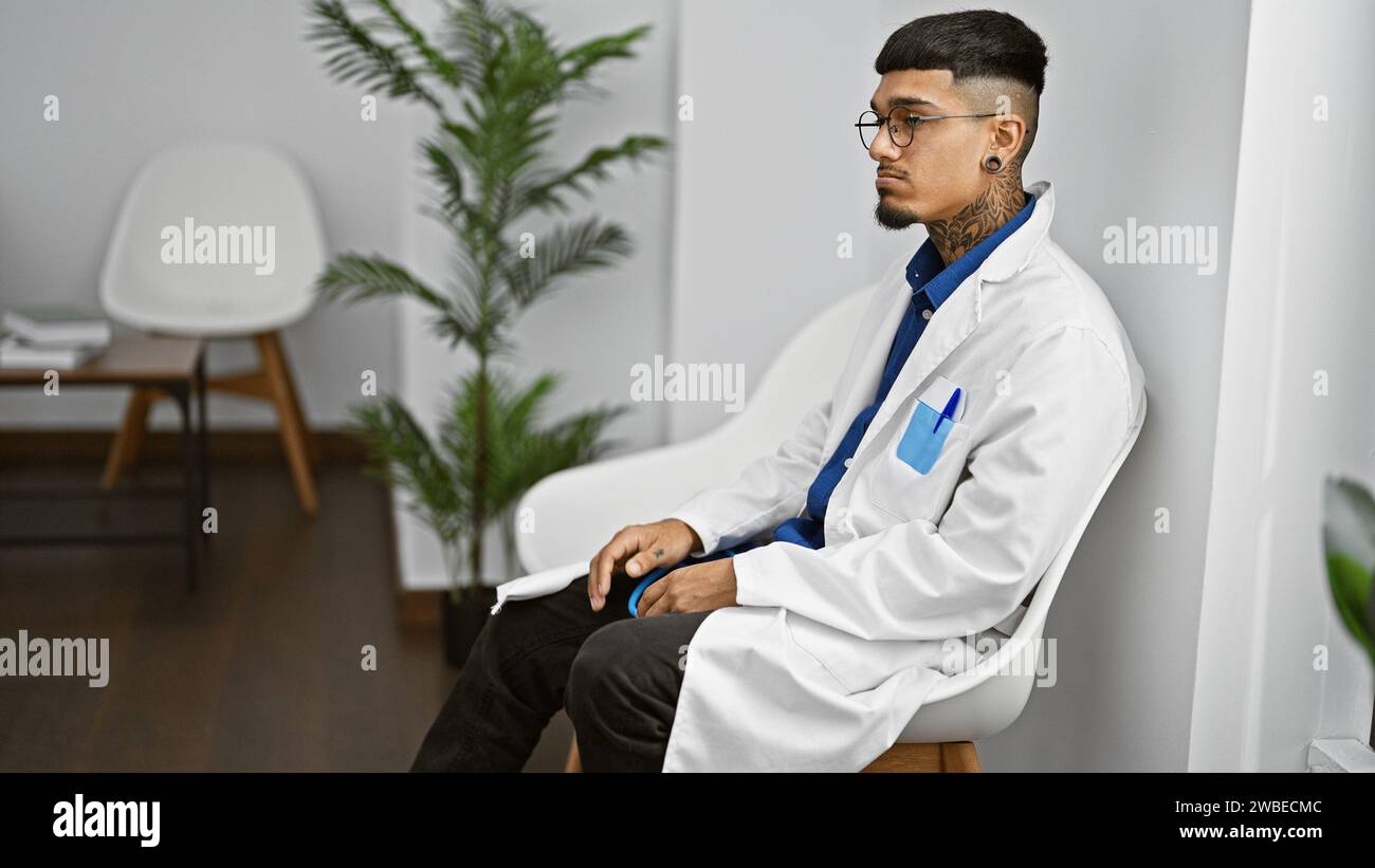 Exhausted young latin doctor in white coat, sitting stressed in the ...