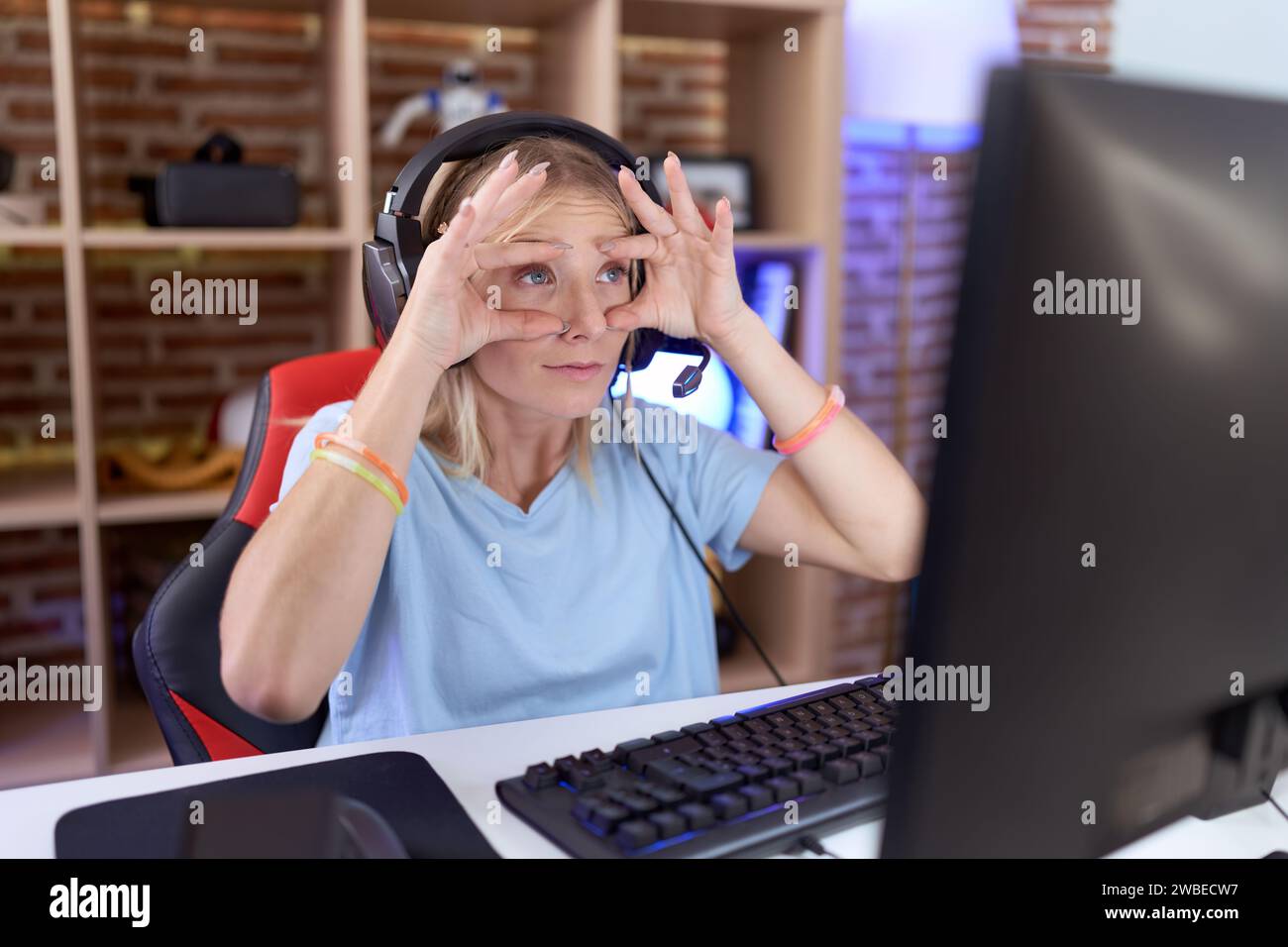 Young caucasian woman playing video games wearing headphones trying to ...