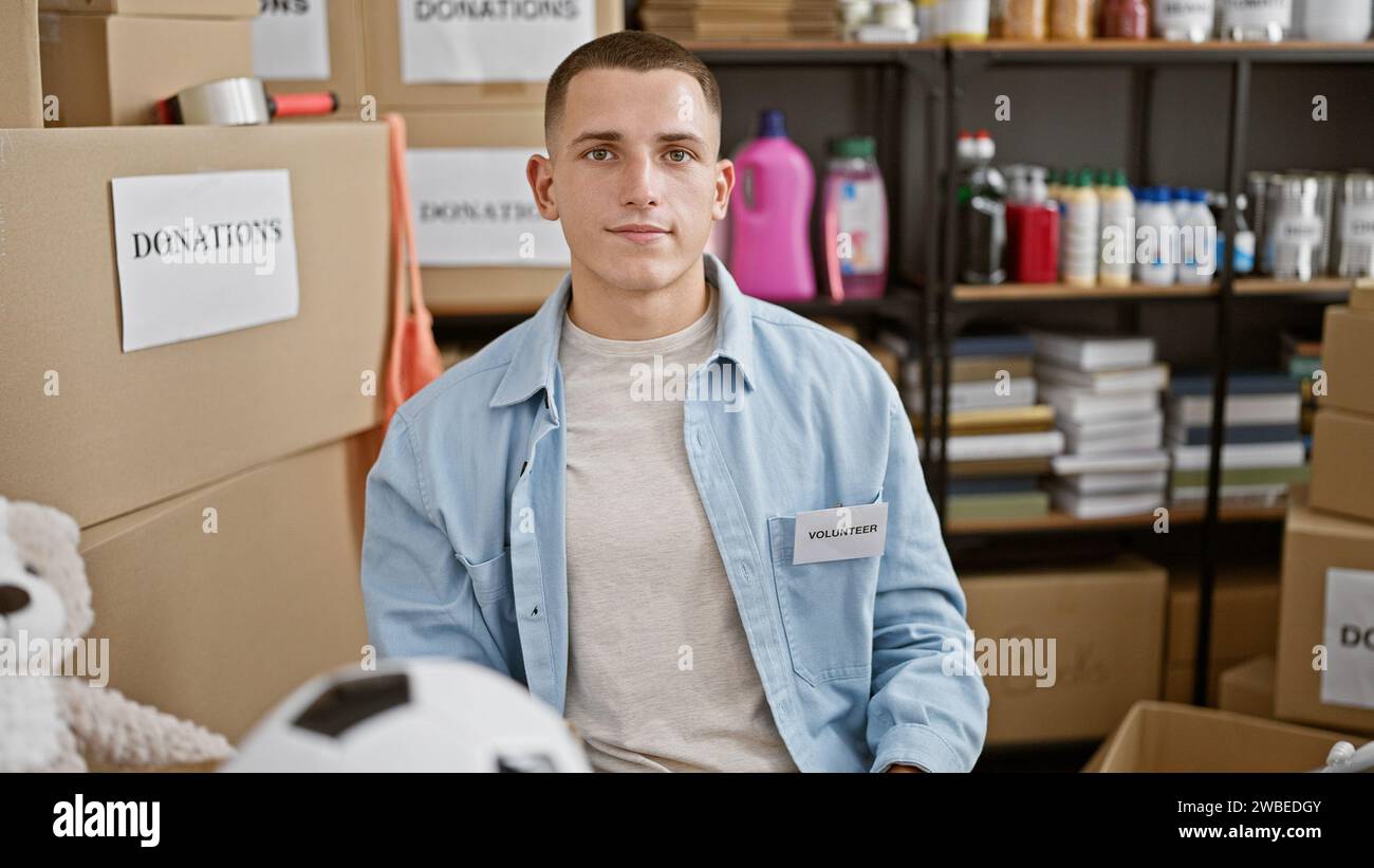 Handsome young man volunteering at an indoor donation center standing ...