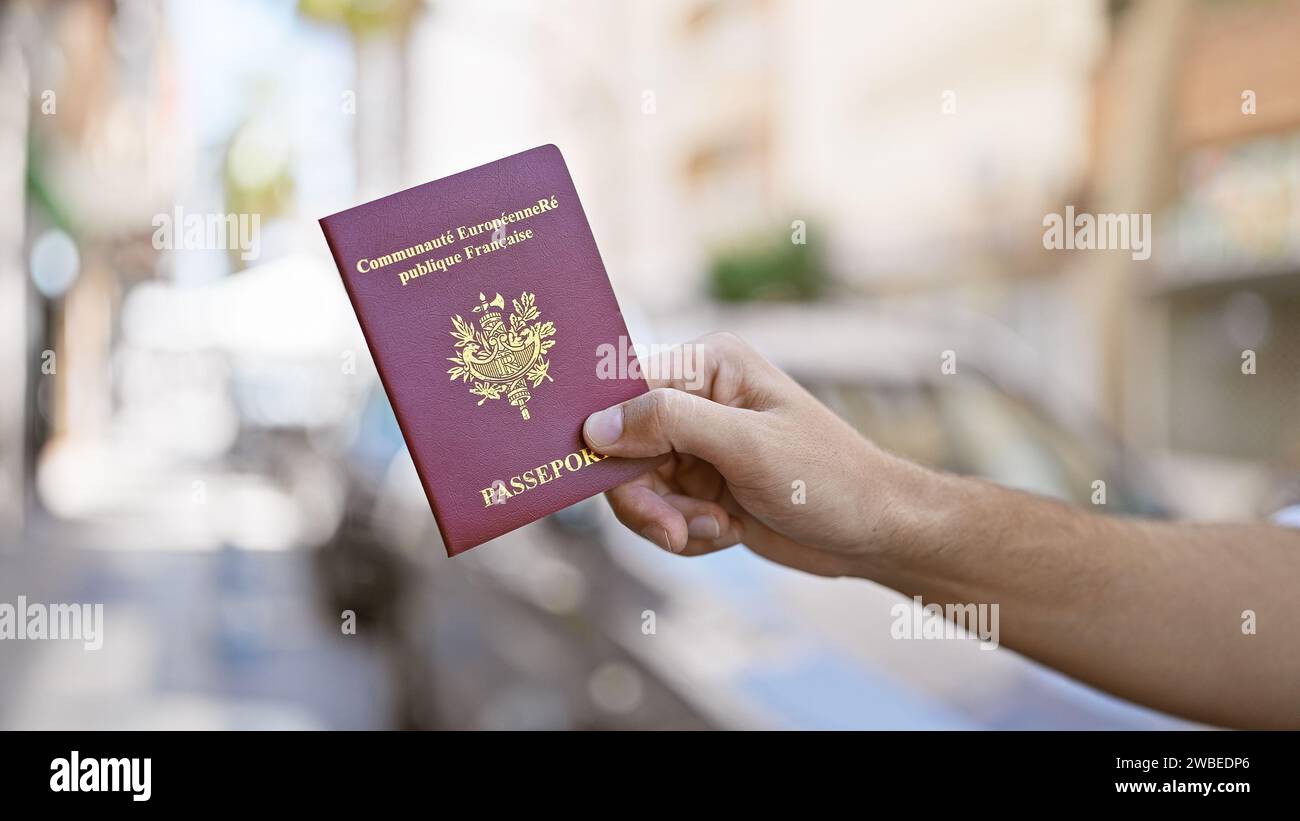 Hand holding french passport on sunlit city street, suggesting urban ...