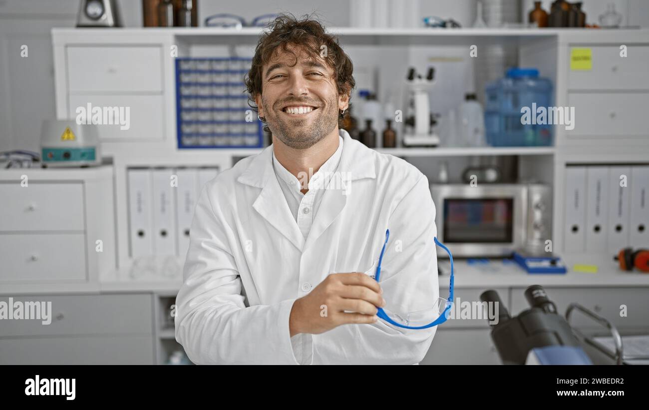 Smiling hispanic man with beard wearing lab coat in a modern laboratory ...