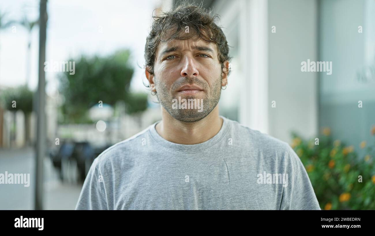 Confident young man with a serious expression, standing in an urban ...