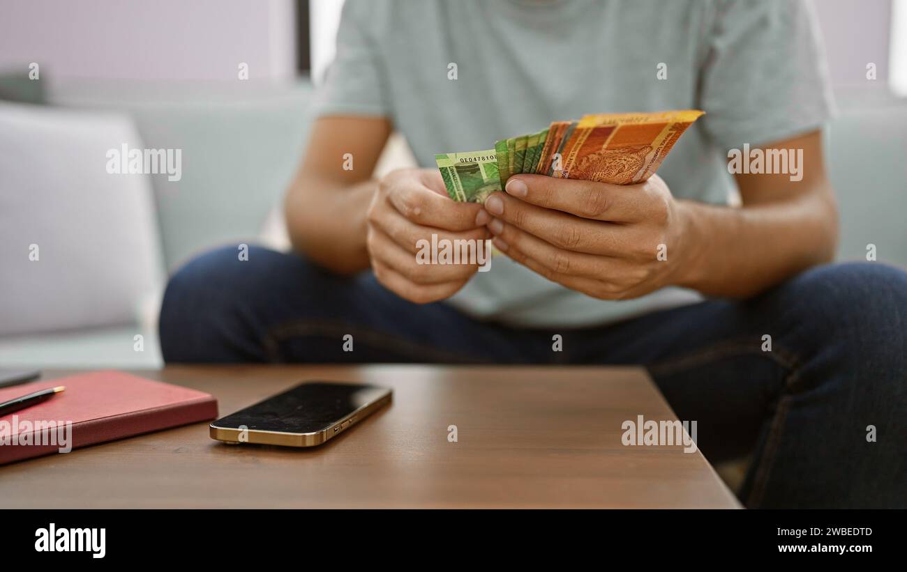 Exciting shot, young man sitting on a sofa at home counting his south ...
