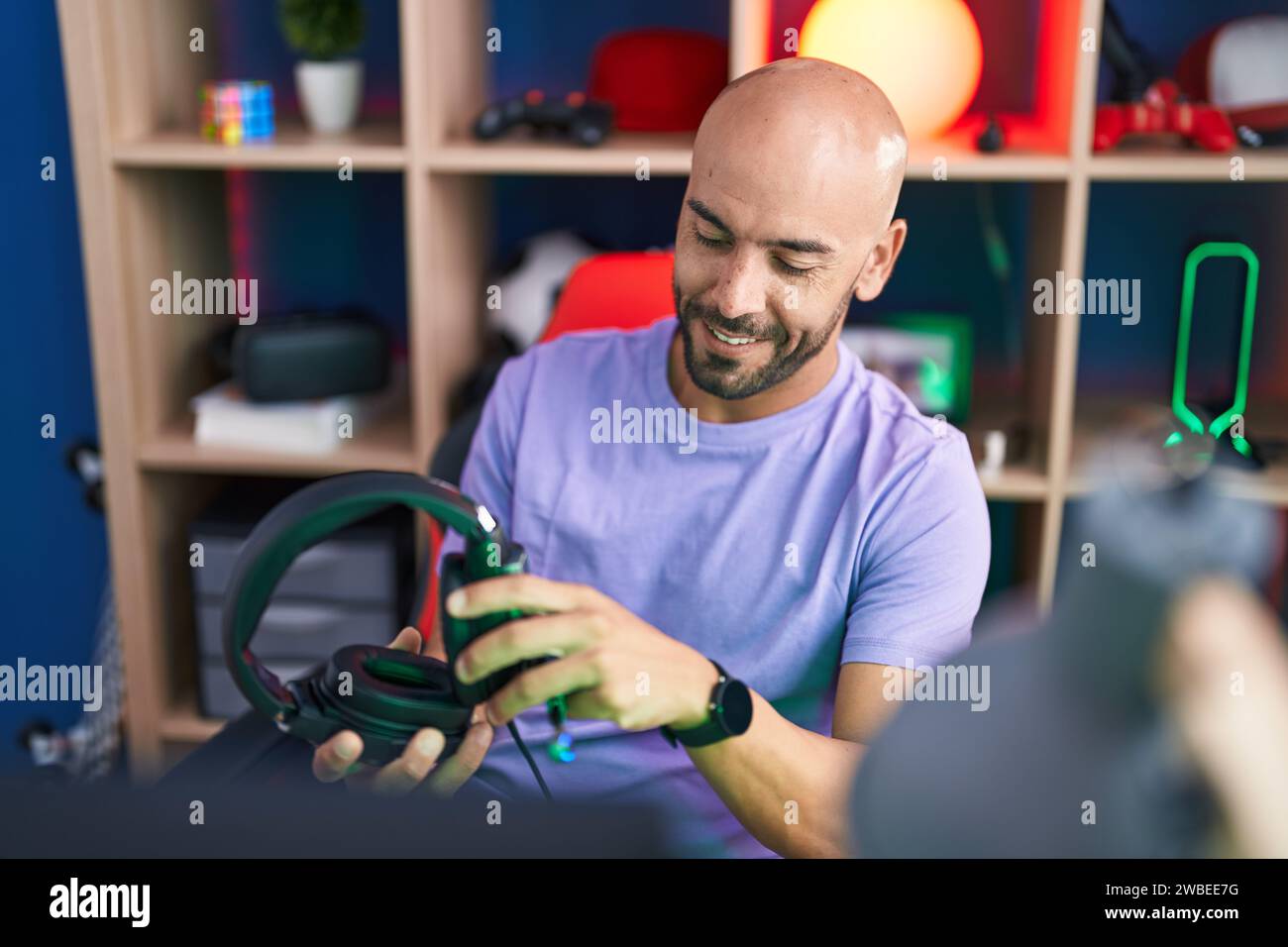 Young bald man streamer smiling confident holding headphones at gaming ...