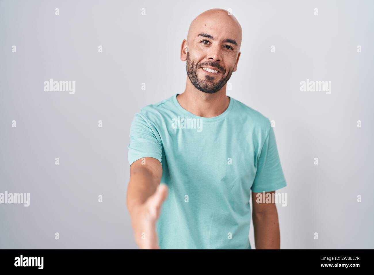 Middle age bald man standing over white background smiling friendly ...