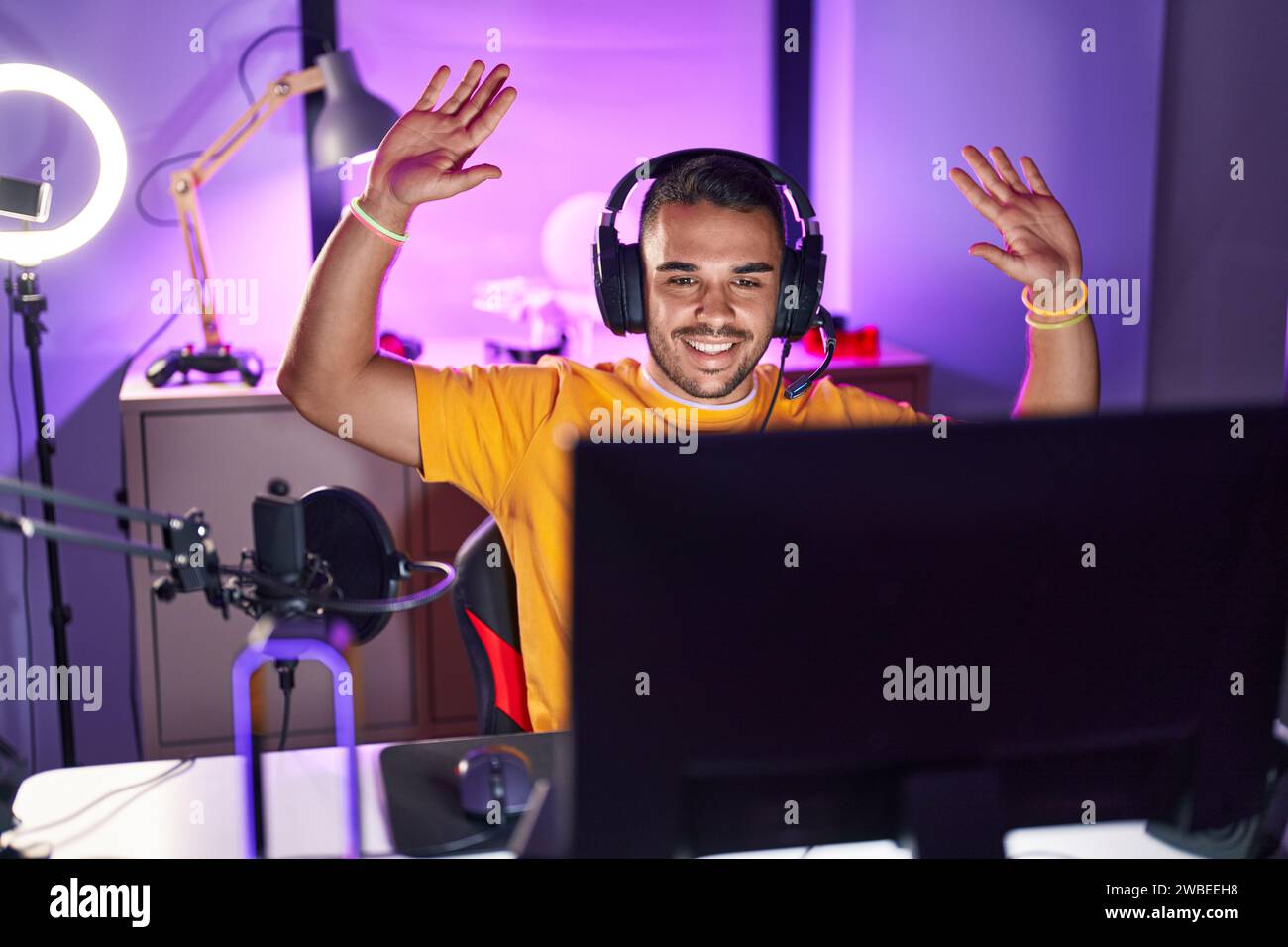 Young hispanic man streamer playing video game dancing at gaming room ...