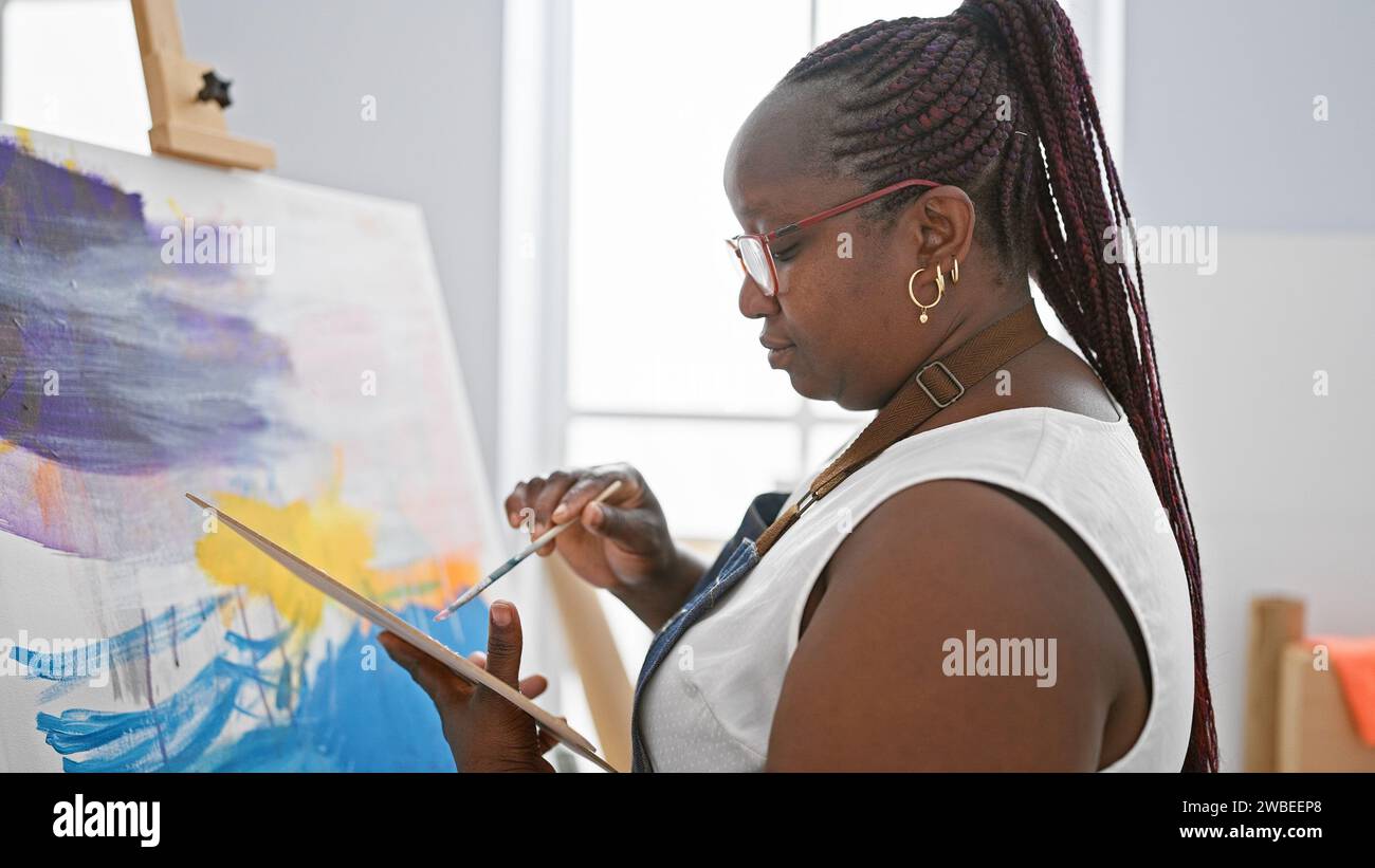 Focused african american woman artist, with braids and glasses ...