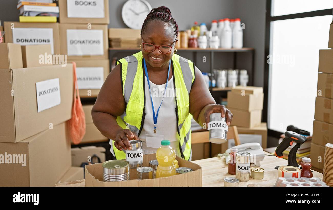 Smiling african american woman volunteering, packing food into ...