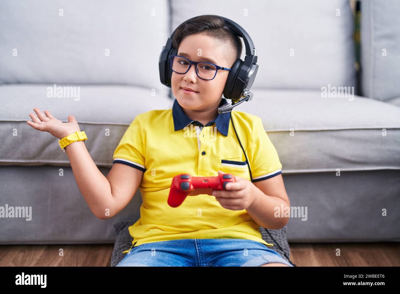 Young hispanic kid playing video game holding controller wearing ...