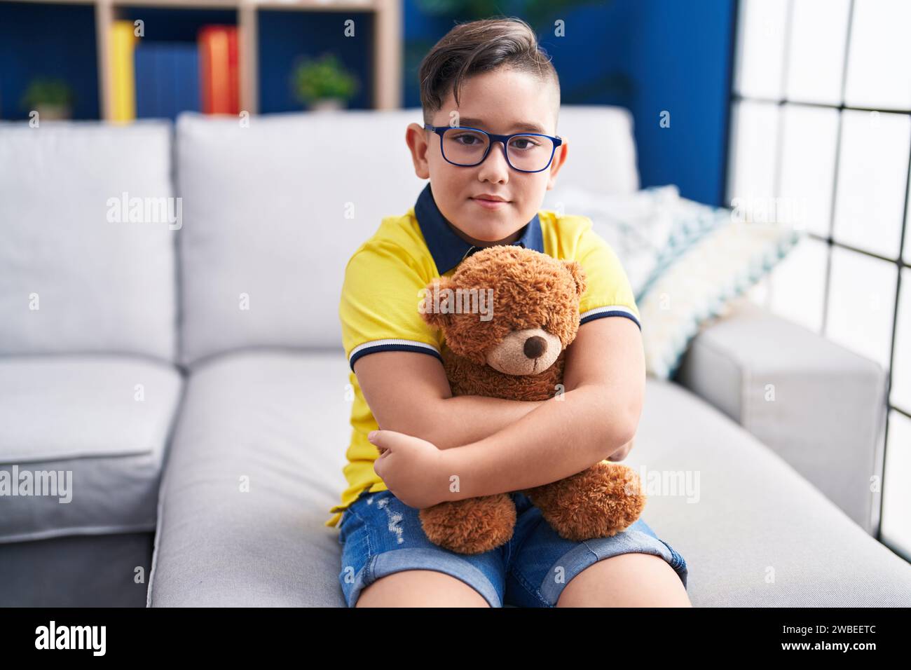 Adorable hispanic boy hugging teddy bear sitting on sofa at home Stock ...