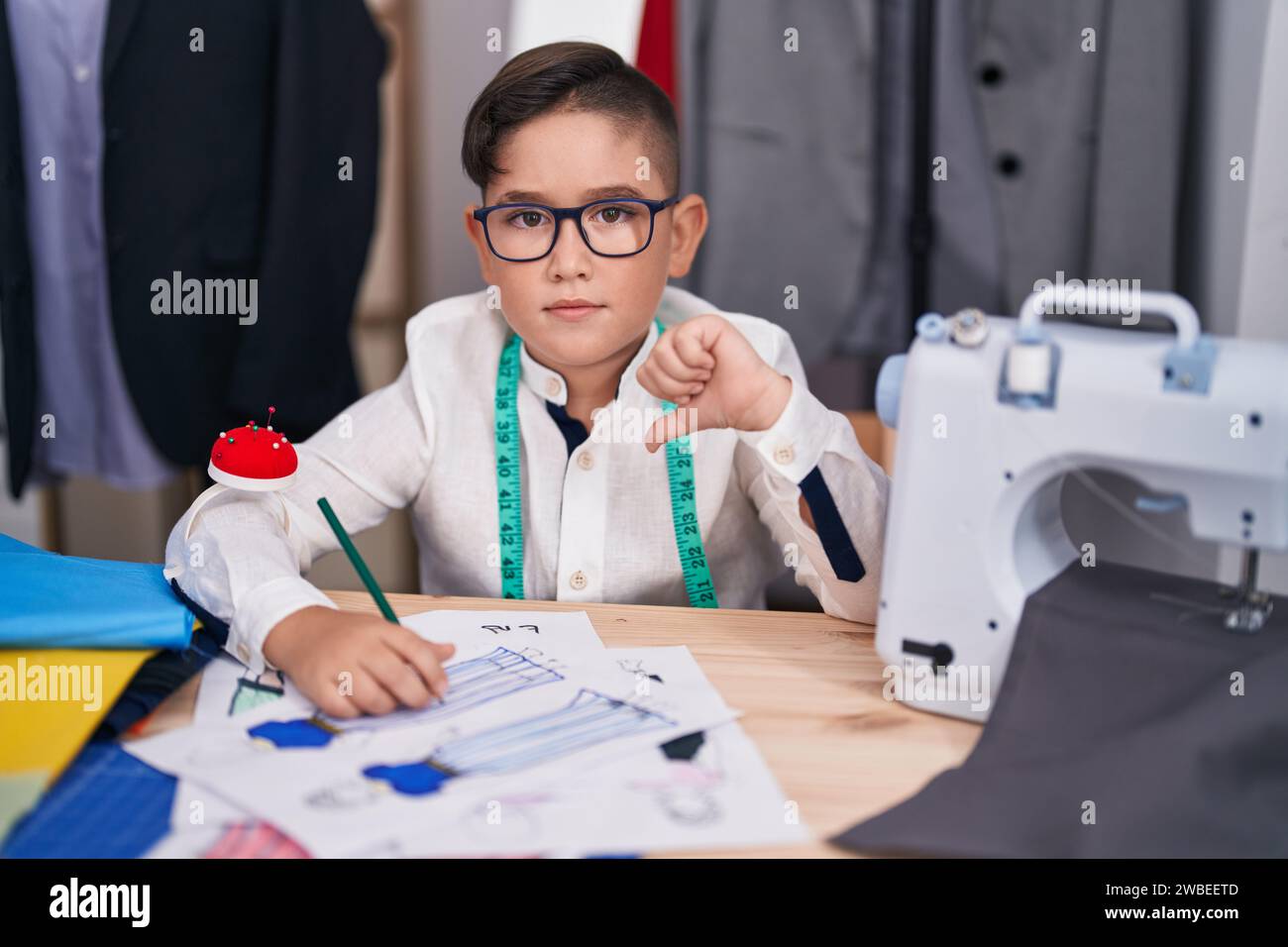 Young hispanic kid at tailor room with angry face, negative sign ...
