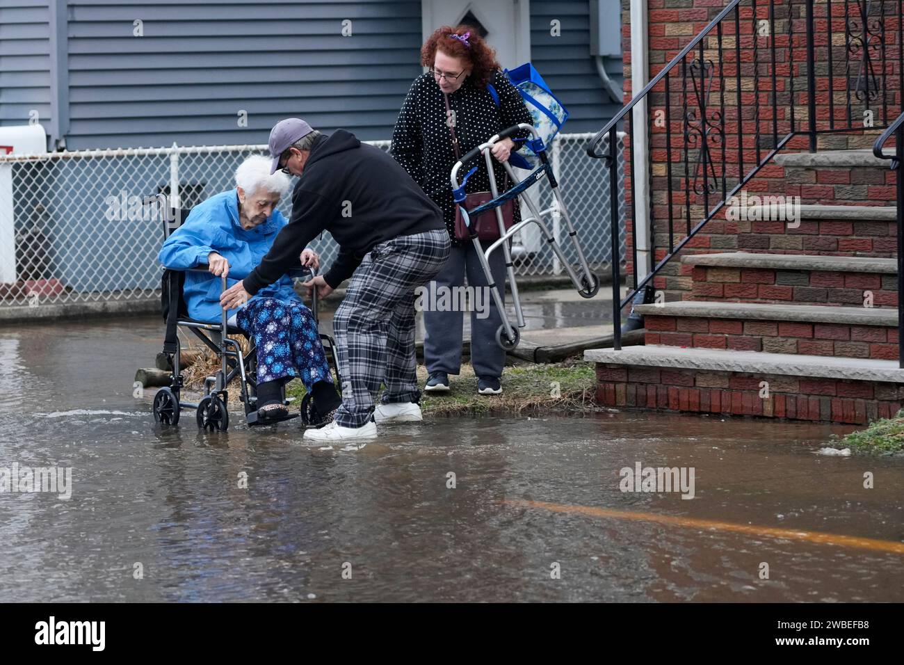 People help a woman in wheelchair through a flooded street in Lodi, N.J ...