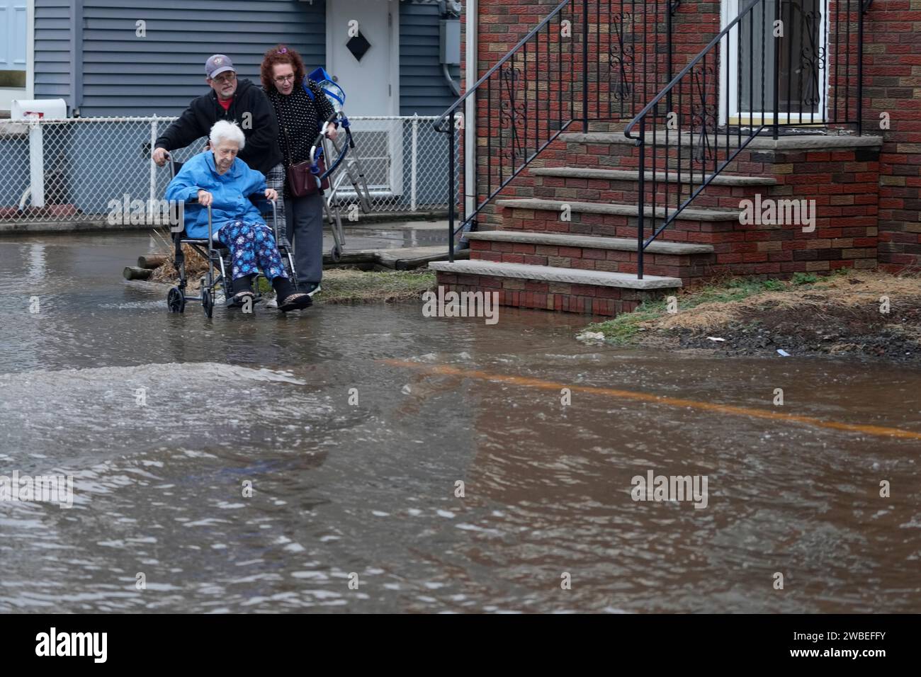 People help a woman in wheelchair through a flooded street in Lodi, N.J ...