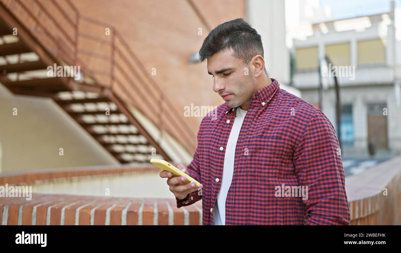 Cool hispanic guy, portrait of a serious young man engrossed in texting ...