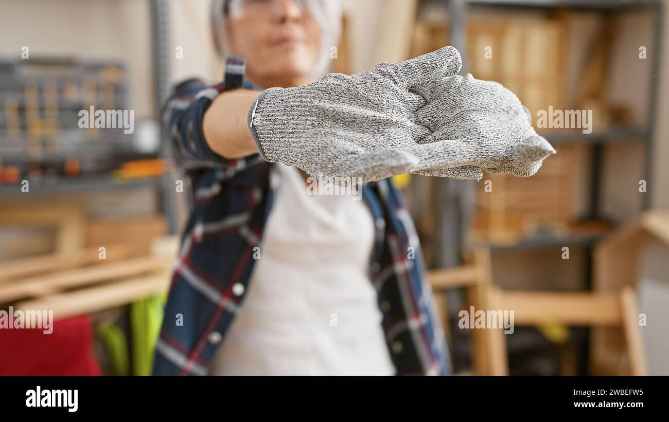 Beautiful grey-haired middle age woman carpenter, stretching arms ...