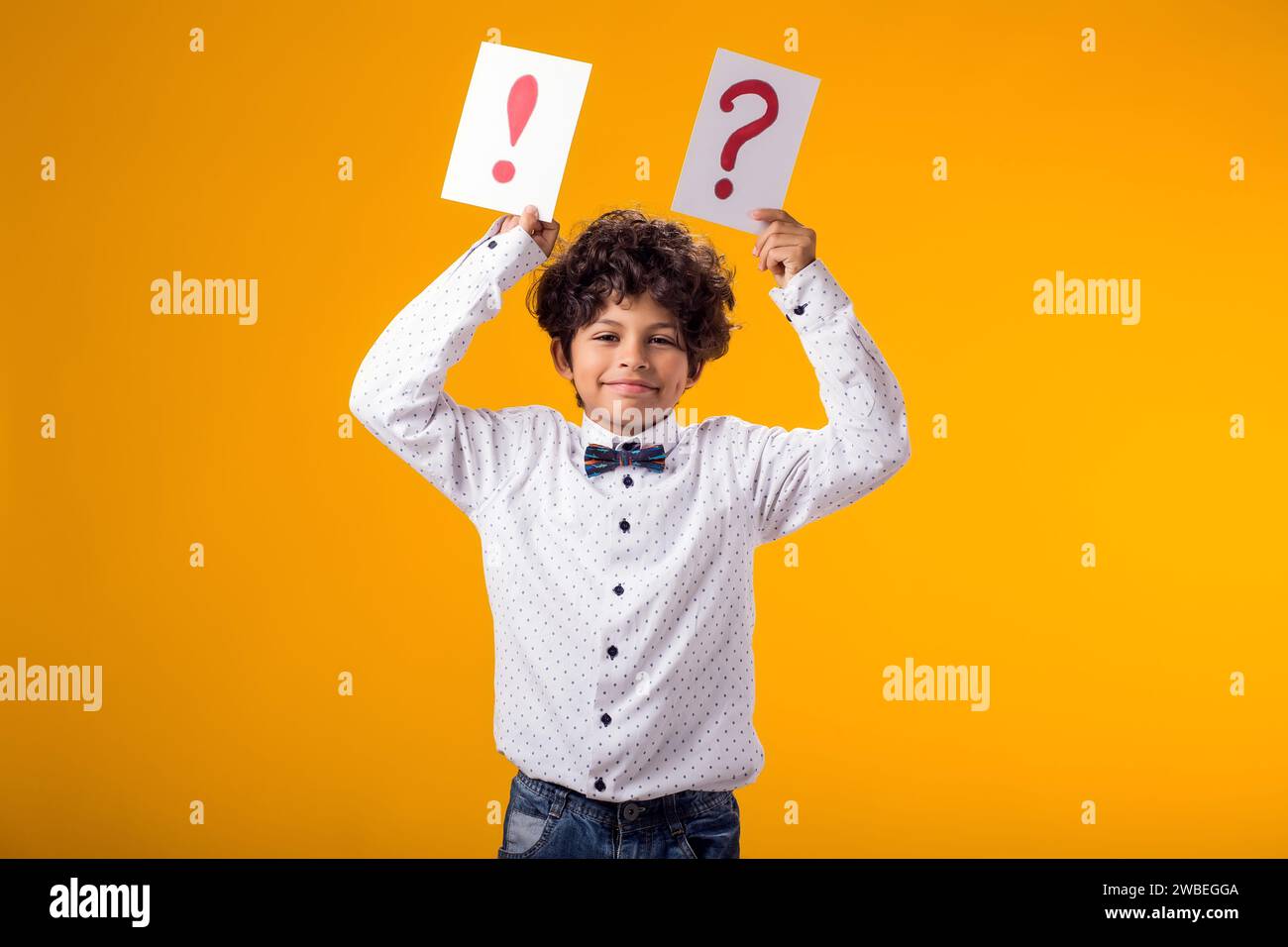 Portrait of child boy holding question mark and exclamation point cards ...