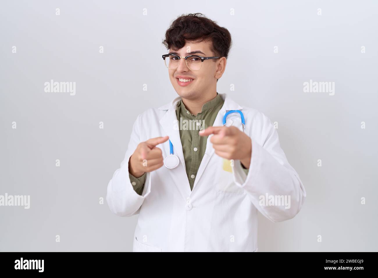 Young non binary man wearing doctor uniform and stethoscope pointing ...