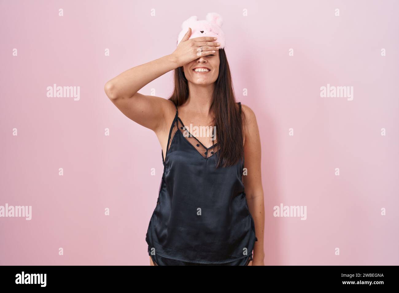 Young brunette woman wearing sleep mask and pyjama smiling and laughing ...