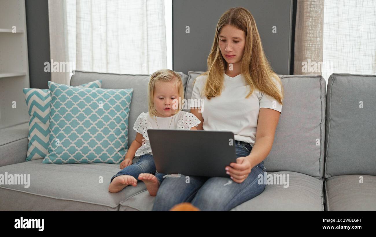 Serious caucasian mother and little daughter engrossed, chilling on ...