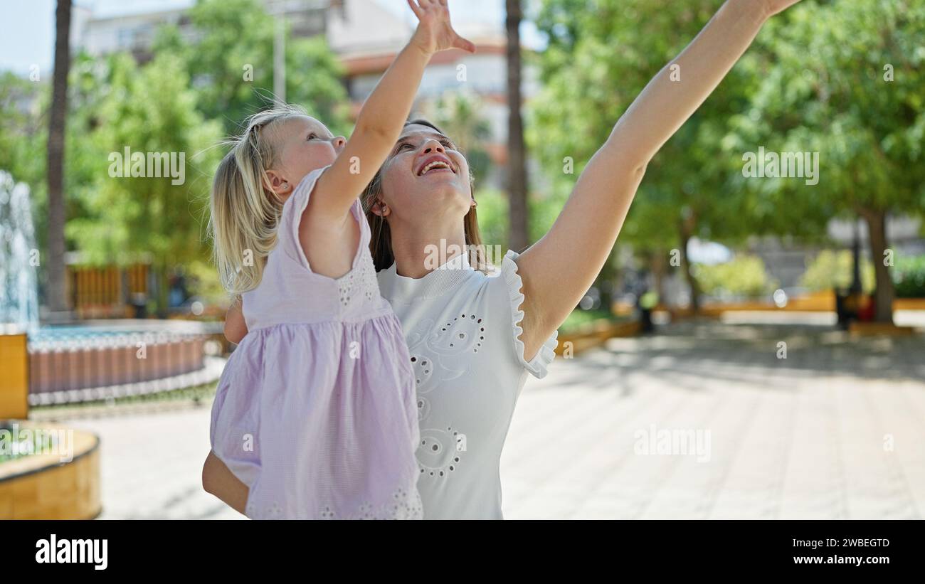 Confident mother holding her cheerful daughter in arms, standing at ...