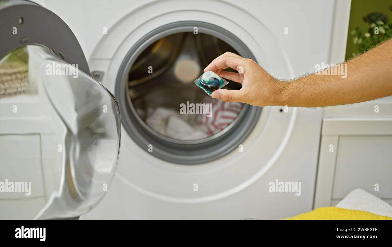 A man uses a laundry pod to wash clothes in a home washing machine ...