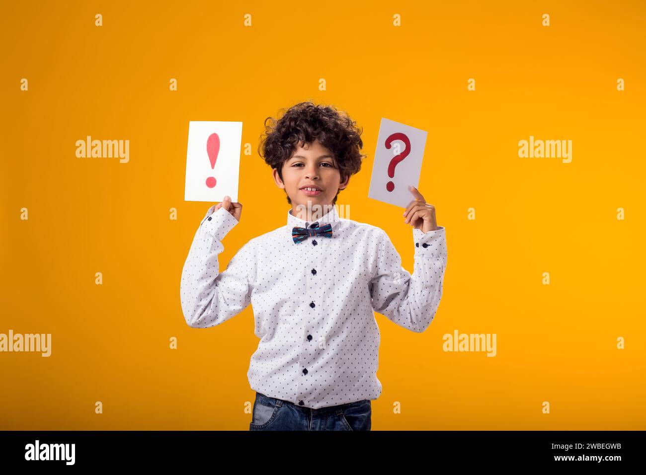 Portrait of child boy holding question mark and exclamation point cards ...