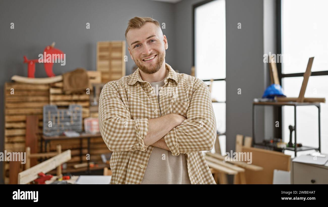 Handsome young bearded man with crossed arms smiling in a bright ...