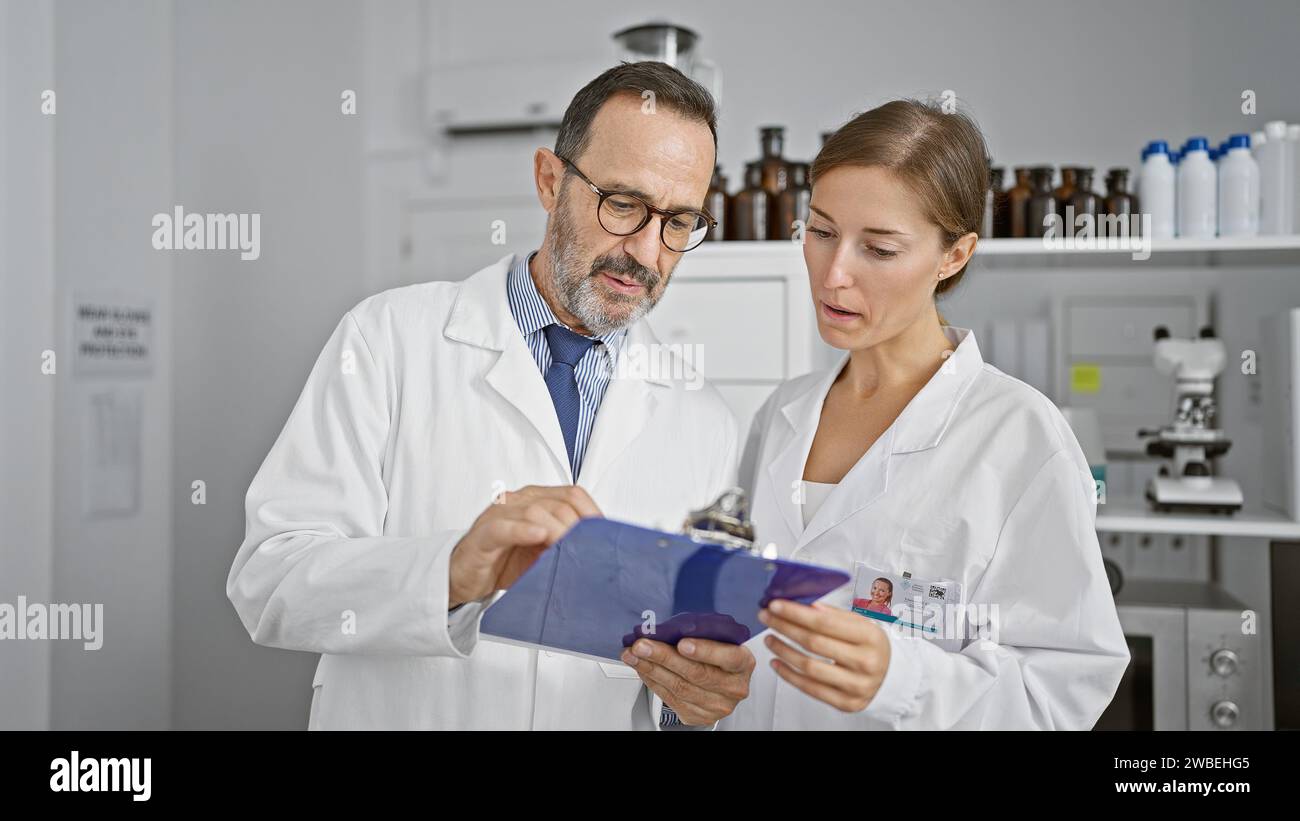 Serious chemists in lab, two science partners engrossed in reading ...