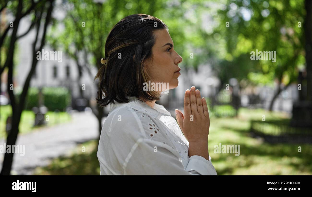 Beautiful young hispanic woman praying and mourning by tombstone at ...