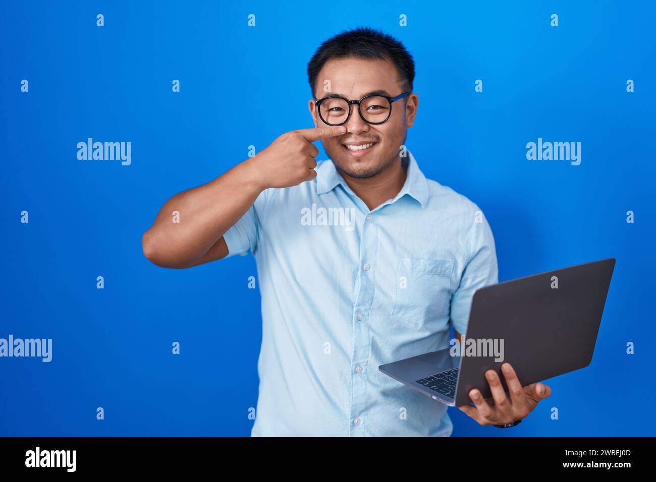 Chinese young man using computer laptop pointing with hand finger to ...