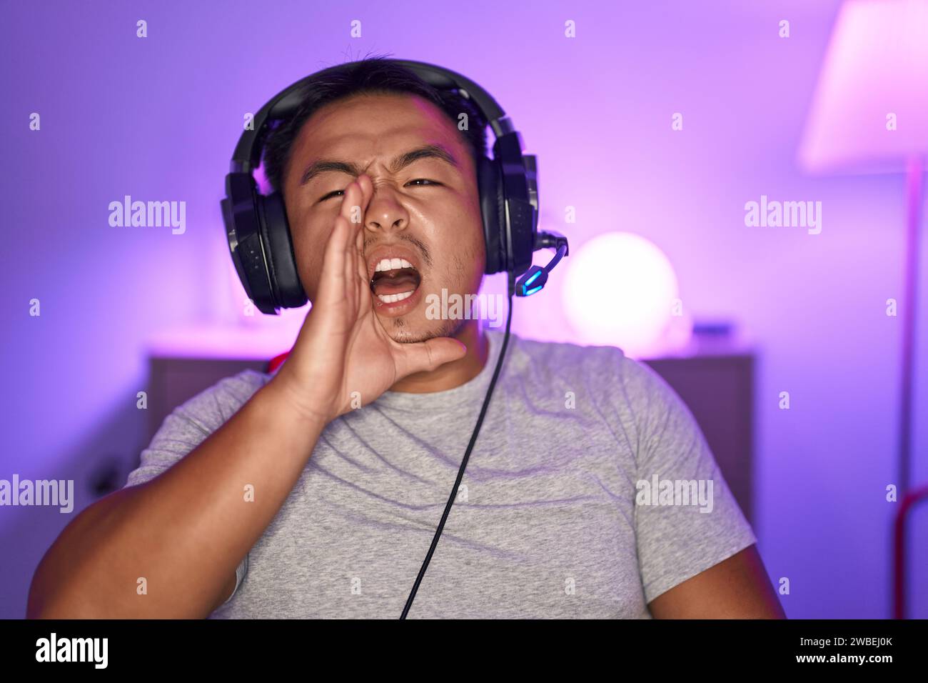 Chinese young man playing video games wearing headphones clueless and ...