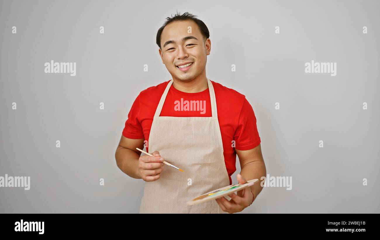Smiling young chinese man, a confident artist, holding his paintbrush ...