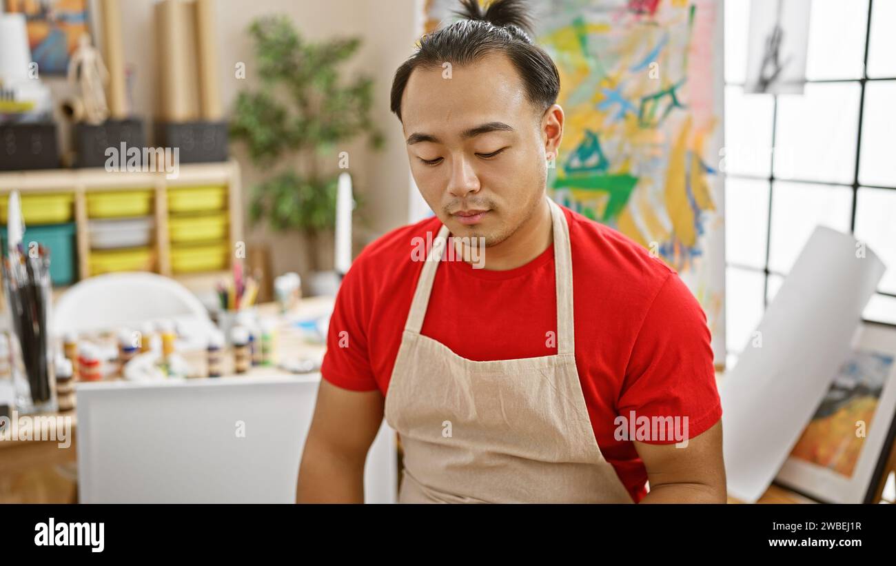 Immersed in creativity, young, serious-faced chinese man artist drawing ...