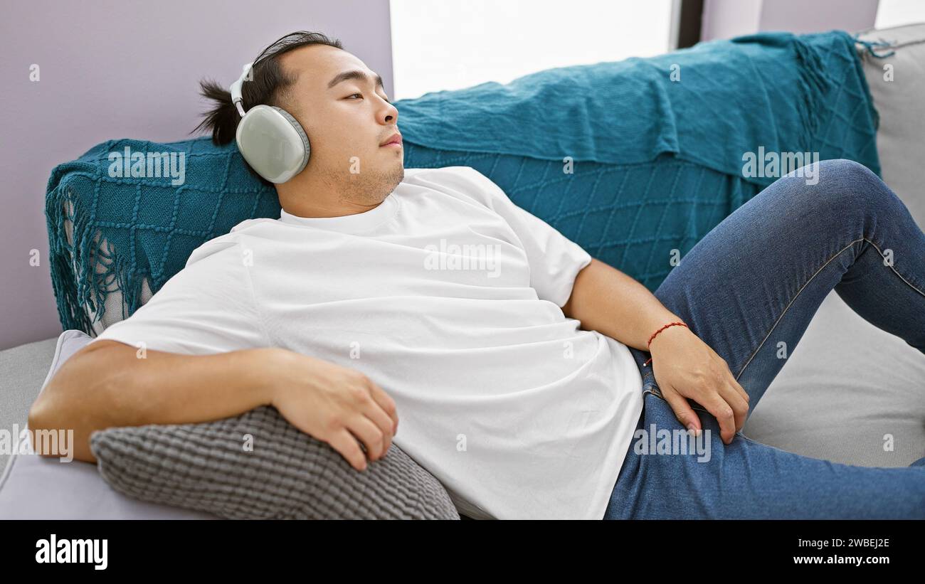 Handsome young chinese man, chilled out while tuned into music on his ...
