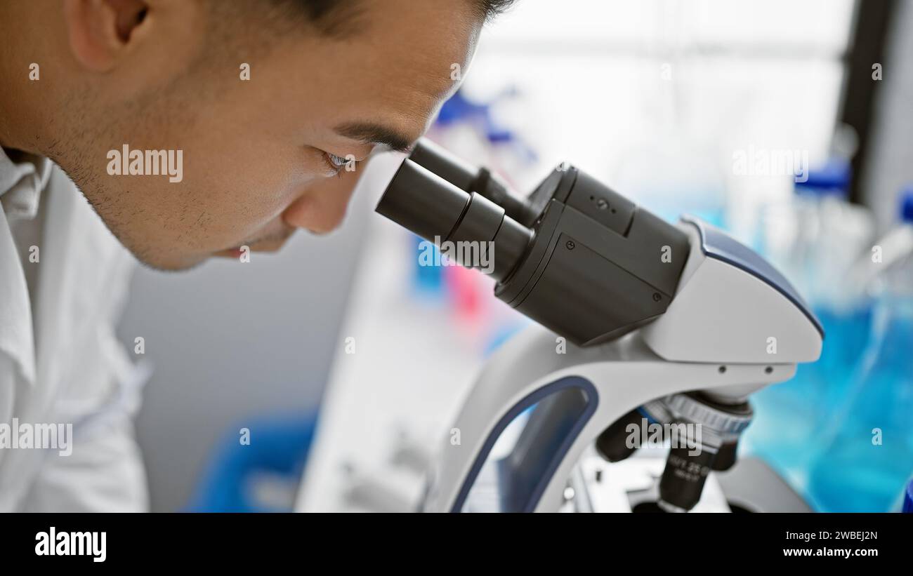 Young chinese man scientist using microscope at laboratory Stock Photo ...
