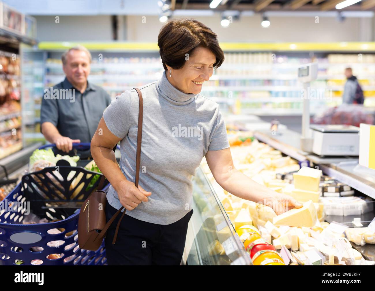Elderly woman choose cheese in supermarket Stock Photo - Alamy