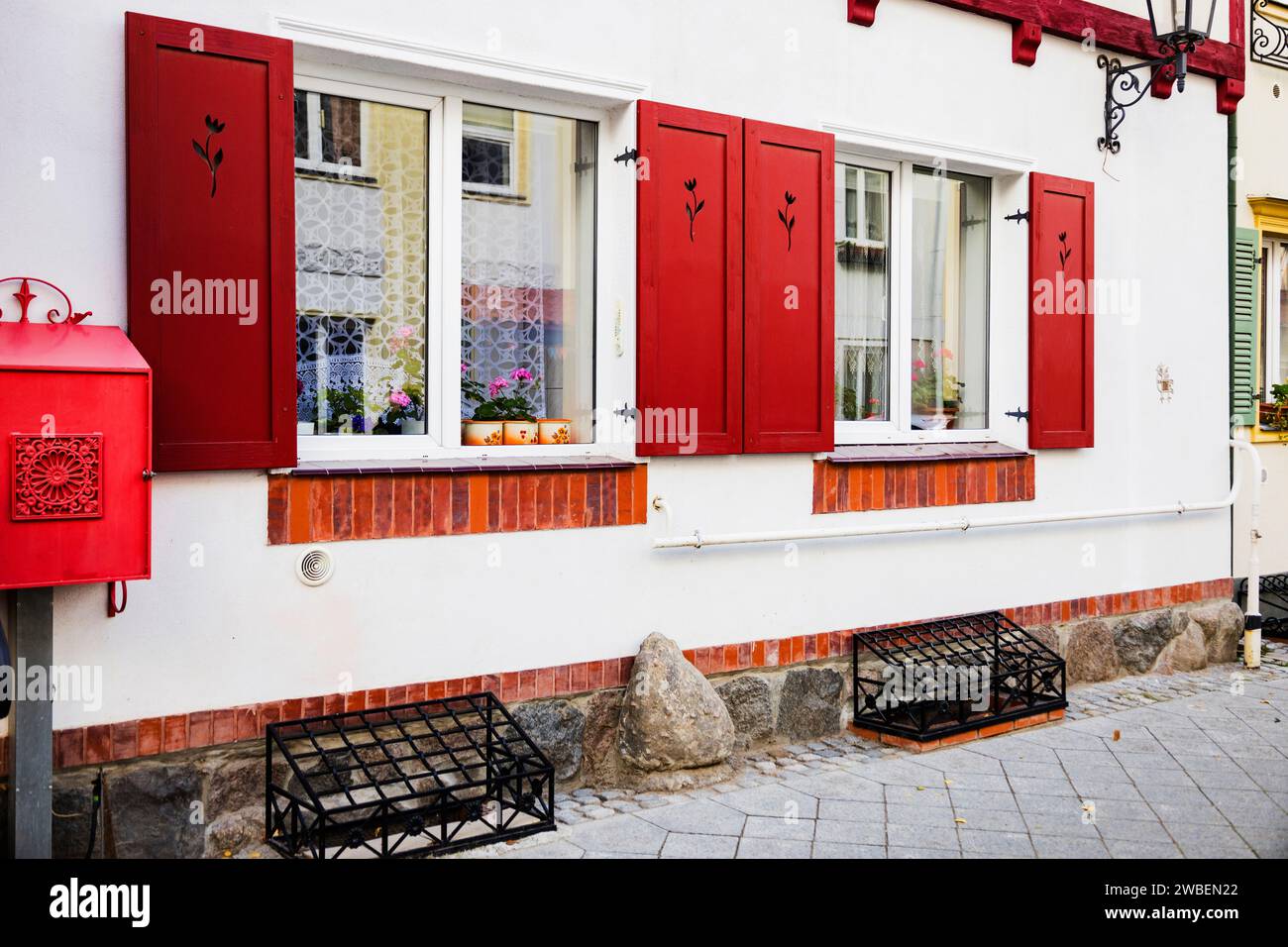 Two Italian windows on the white wall facade with open red color ...