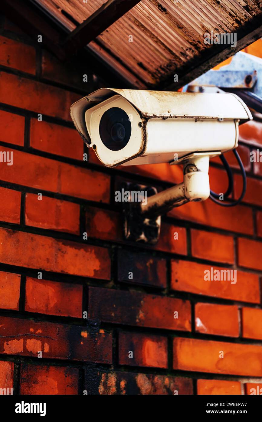 Old worn surveillance camera equipment mounted on red brick wall ...